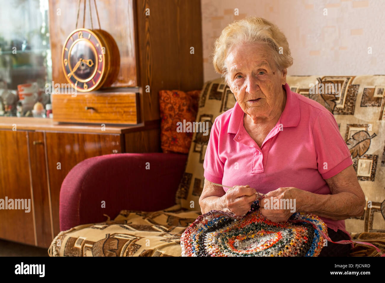 An elderly woman sitting in her room and knitting rug Stock Photo - Alamy