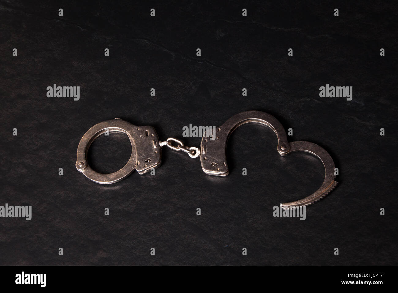 Handcuffs on a black background Stock Photo - Alamy