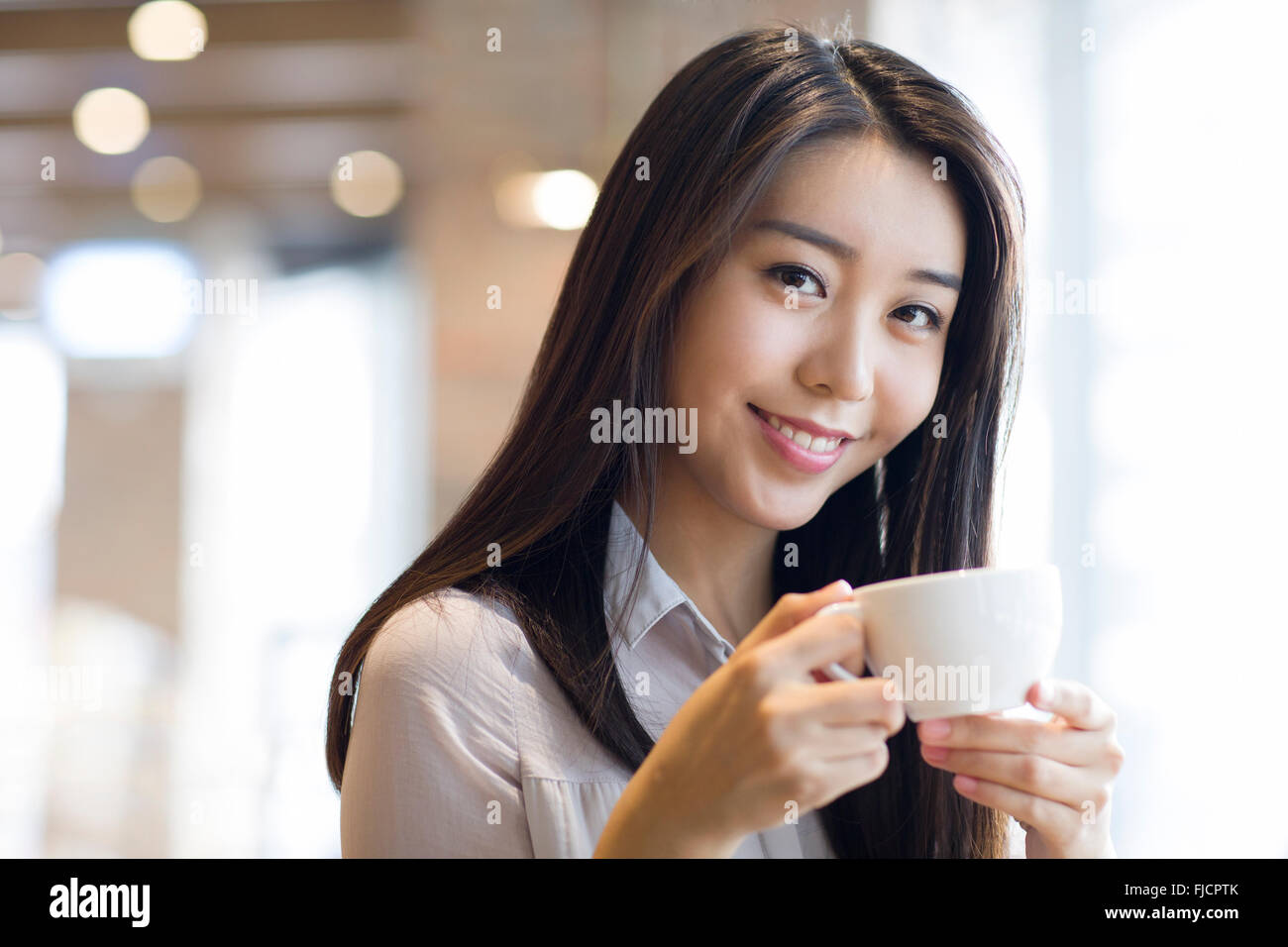 Young Chinese woman drinking coffee in café Stock Photo - Alamy
