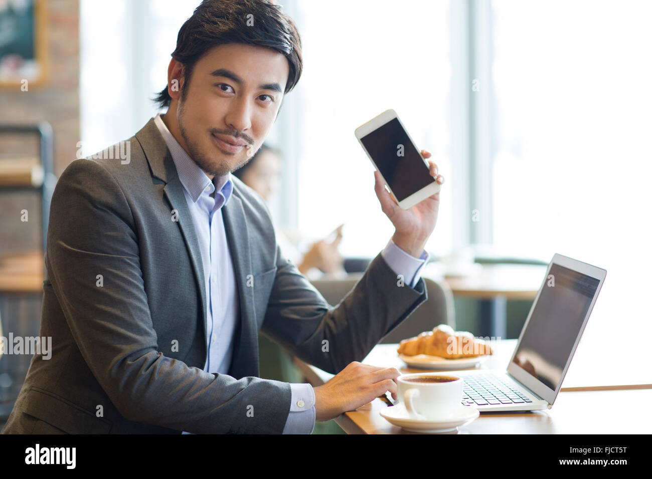 Chinese businessman showing smart phone in café Stock Photo - Alamy