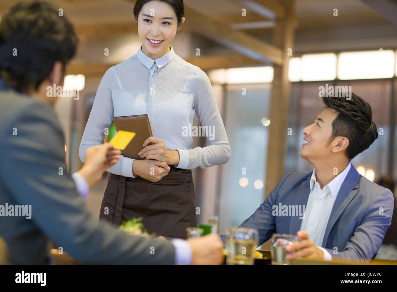 Chinese Businessman Paying Bill By Credit Card In Restaurant Stock