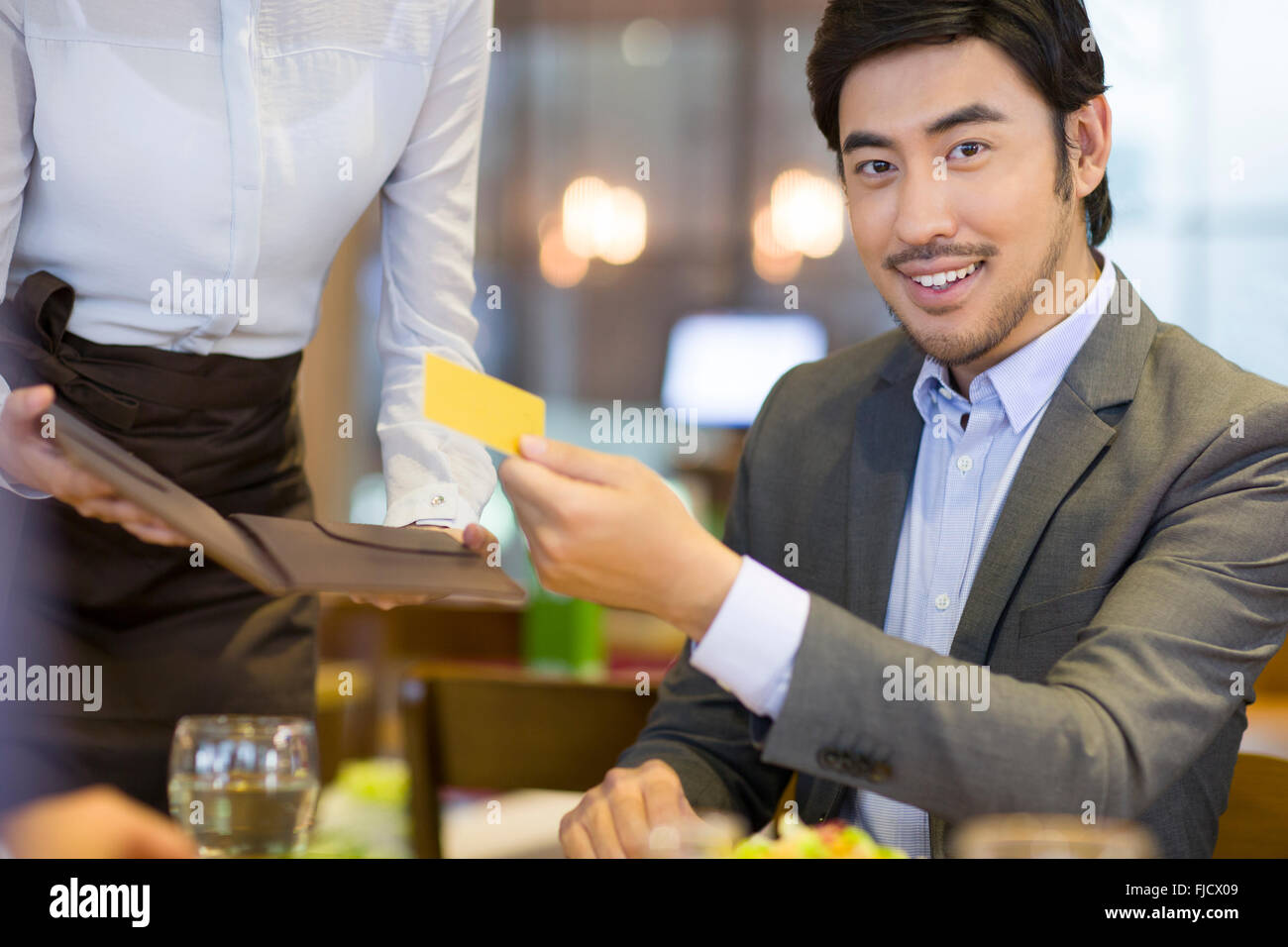 Chinese Businessman Paying Bill By Credit Card In Restaurant Stock