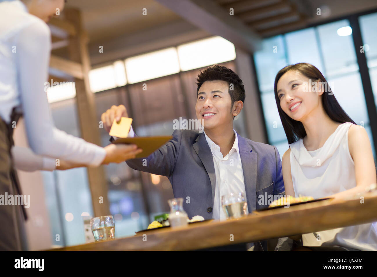 Young Chinese man paying bill by credit card in restaurant Stock Photo ...