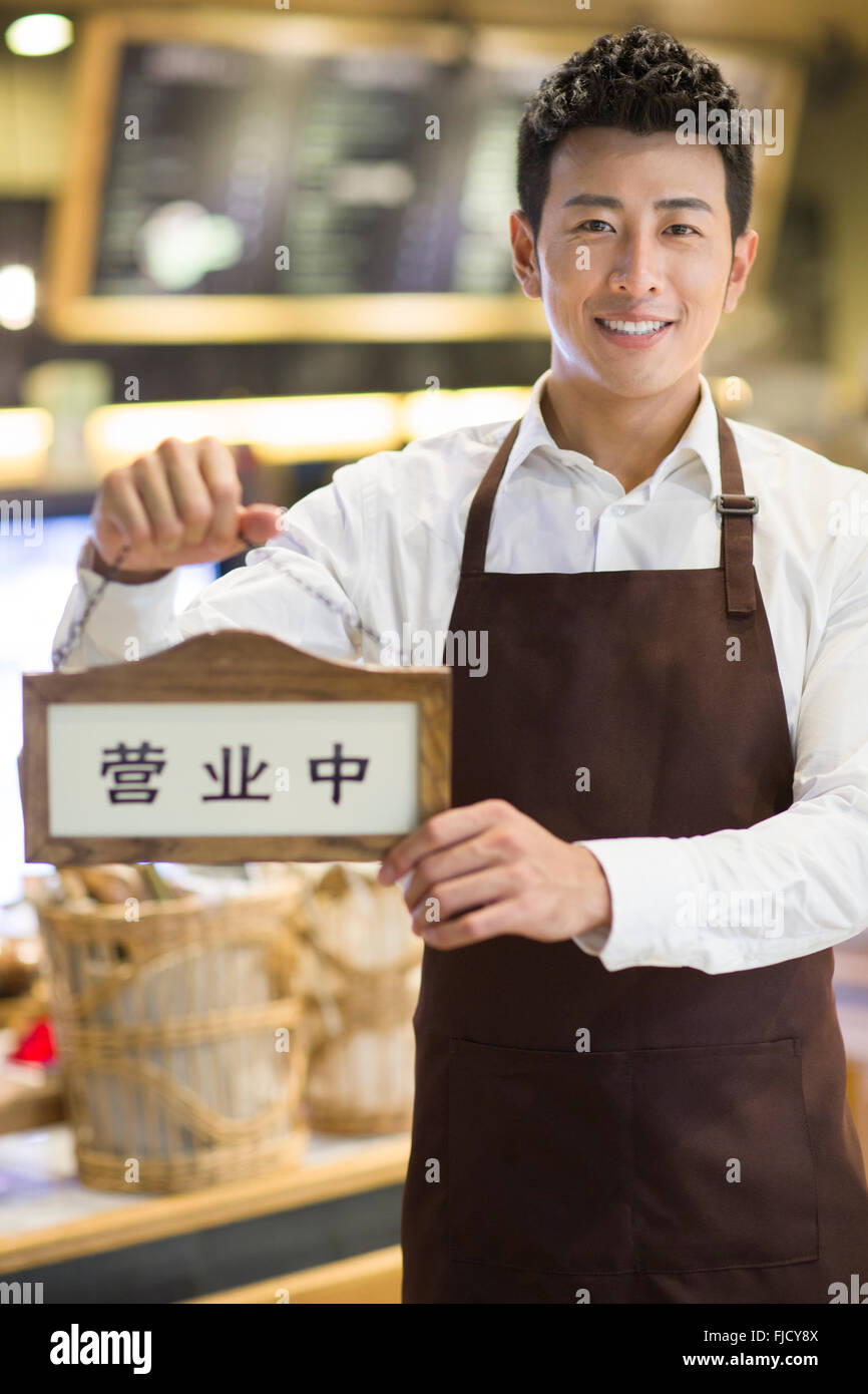 Young Chinese man holding an open sign Stock Photo - Alamy