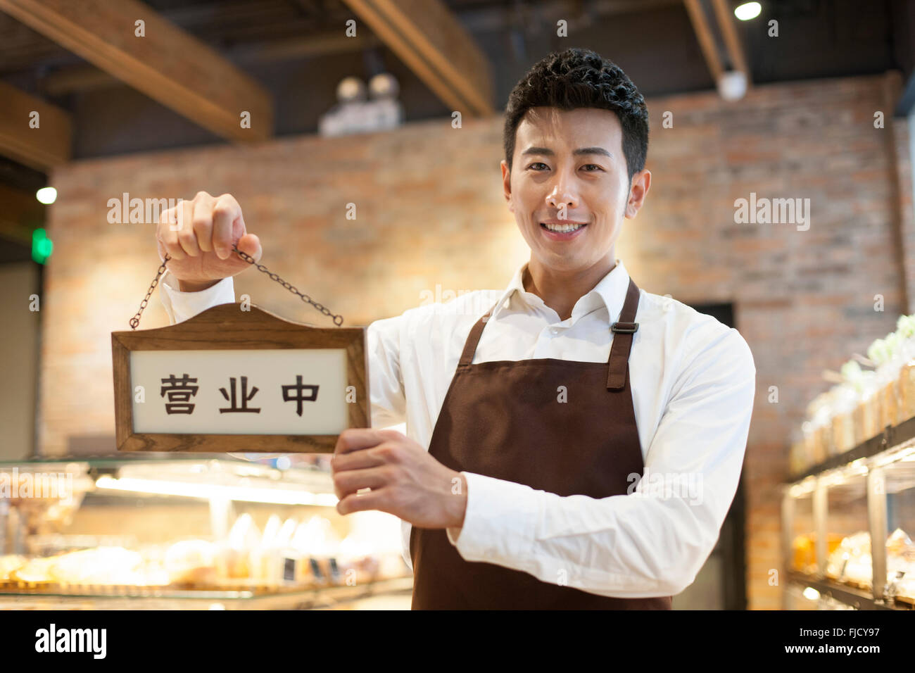 Young Chinese man holding an open sign Stock Photo - Alamy