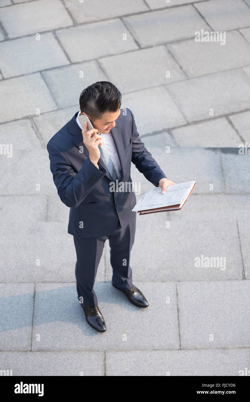 Overhead view of a Chinese Business man Outside Office using his Mobile ...
