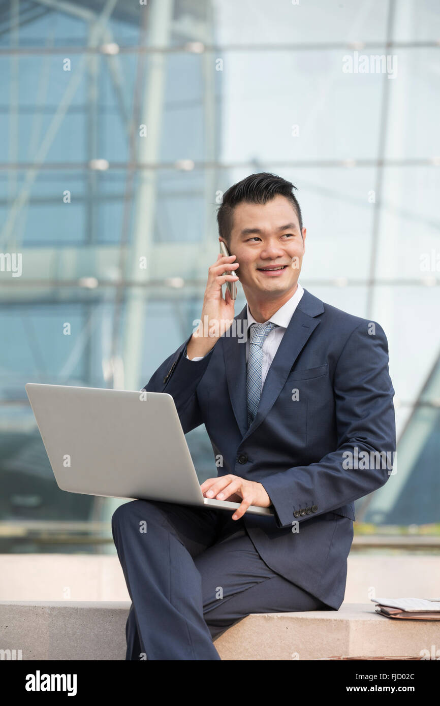 Chinese business Man using his laptop out doors in modern city Stock ...