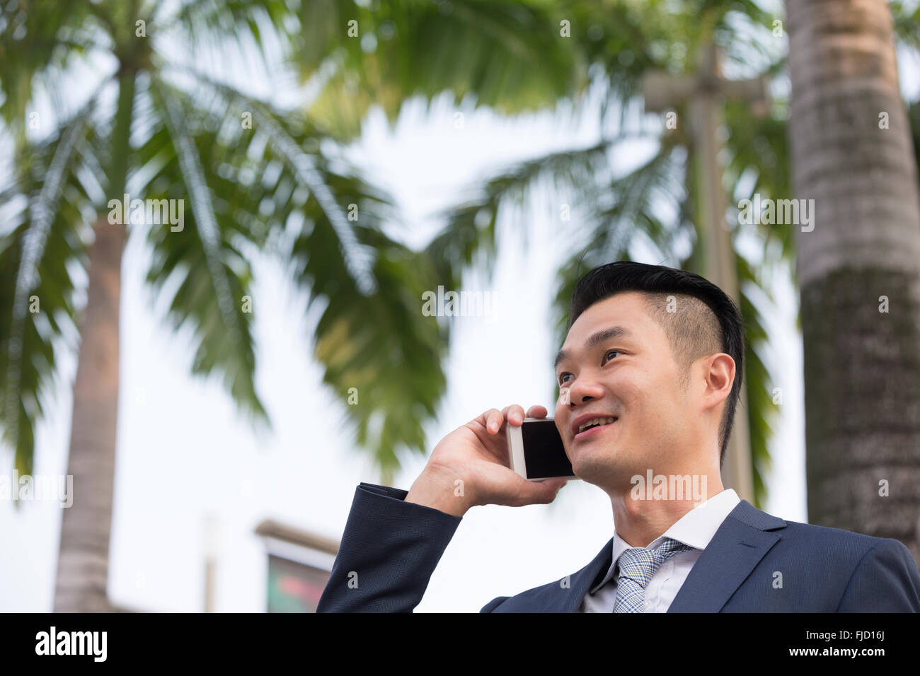 Cheerful Asian/Chinese business man using his smart phone in urban city ...