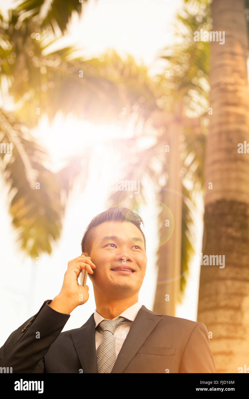 A portrait of a happy Chinese business man talking on the phone ...