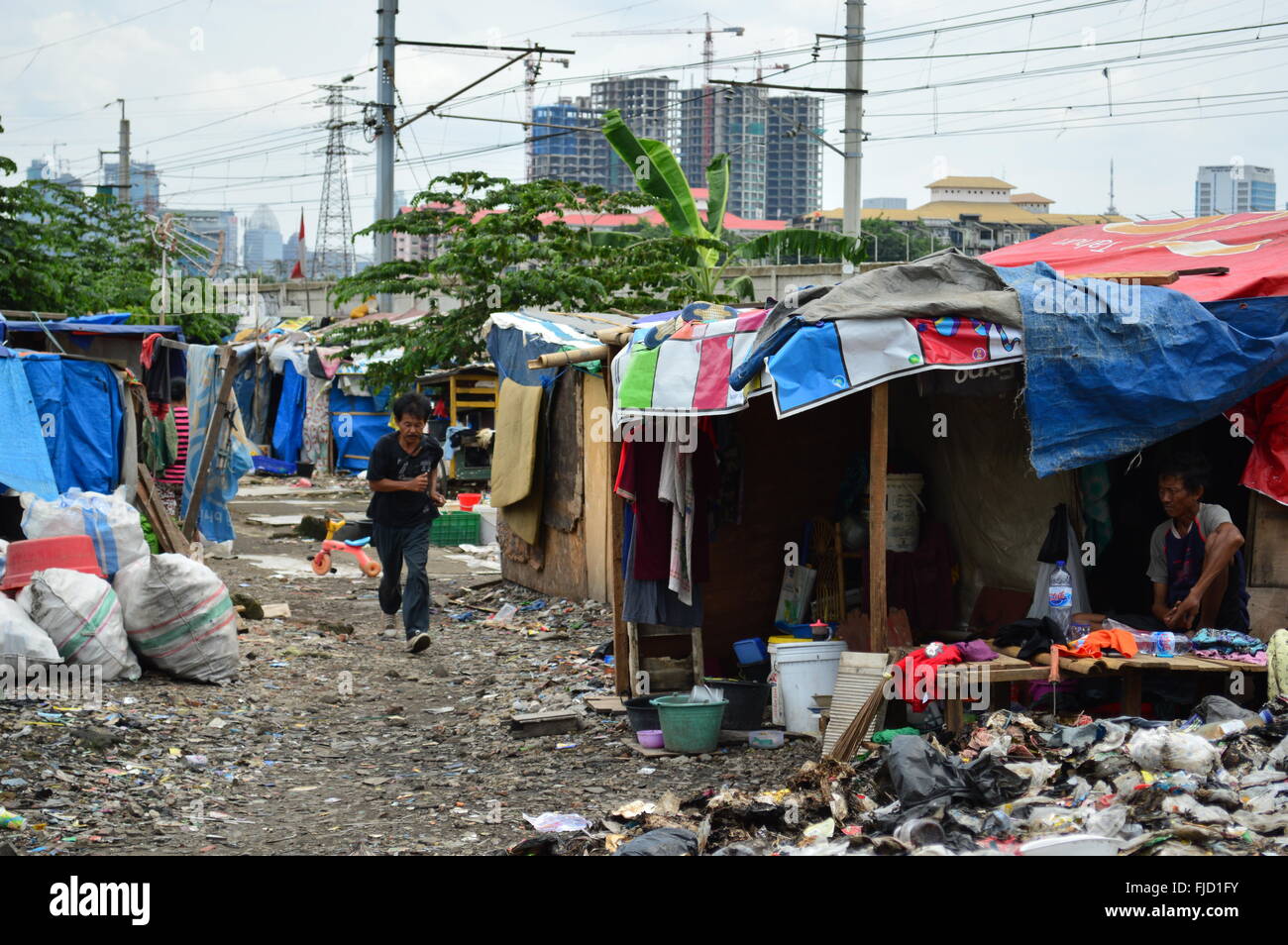 Canvas used as roof of slum house with tall skyscrapers behind, Jakarta ...