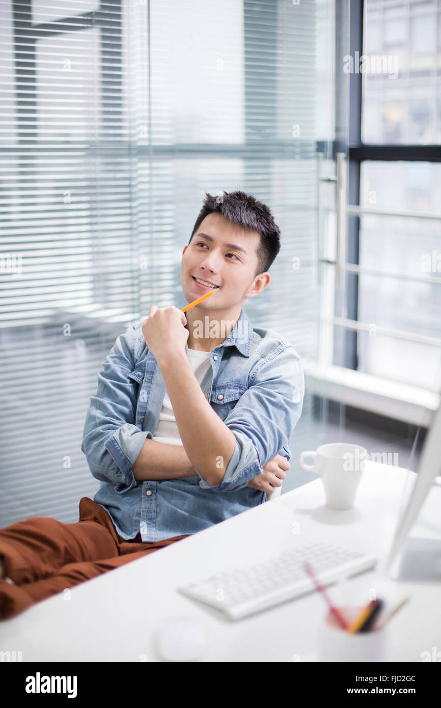 Young Chinese man thinking in office Stock Photo - Alamy
