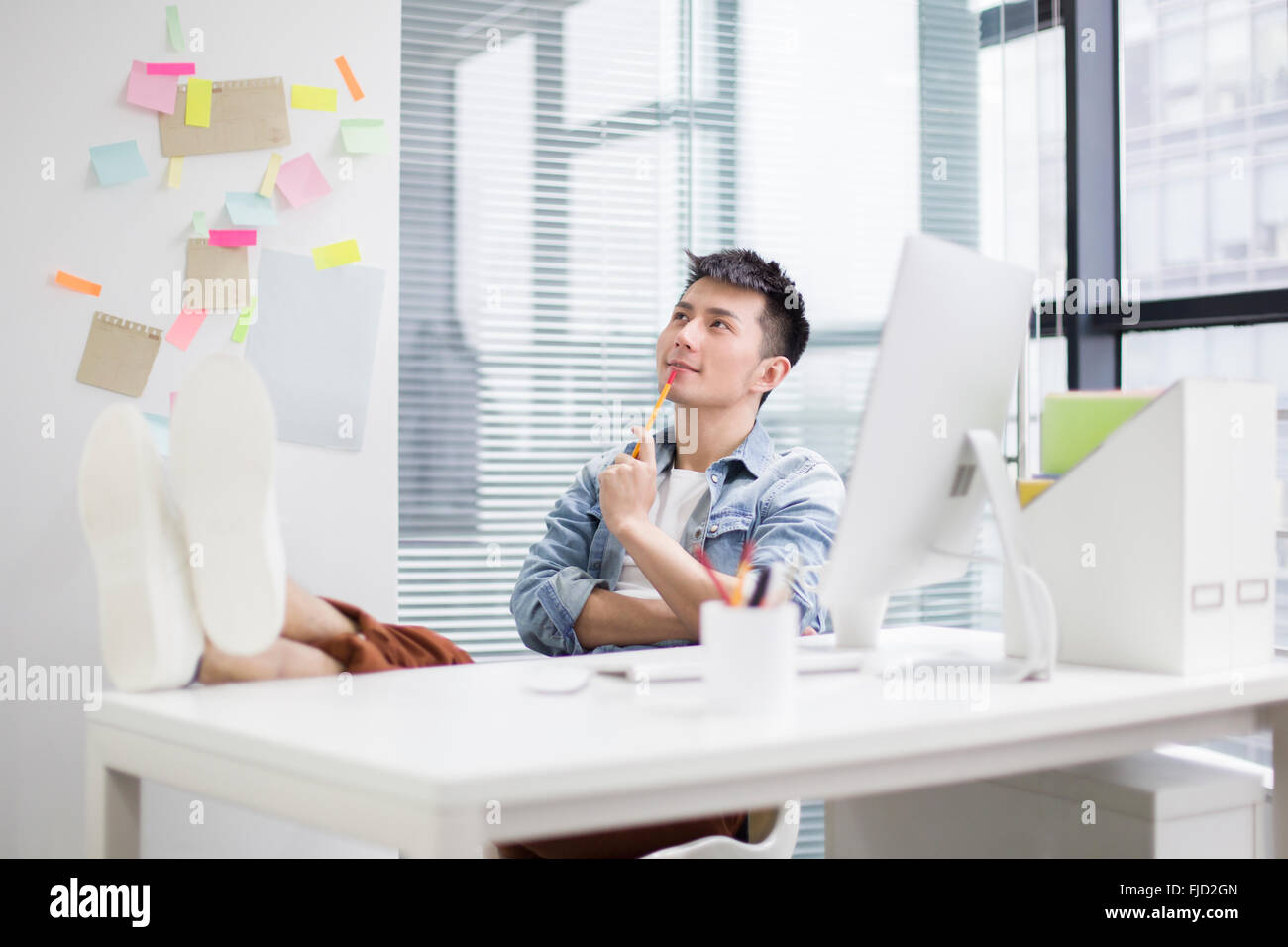 Young Chinese man thinking in office Stock Photo - Alamy