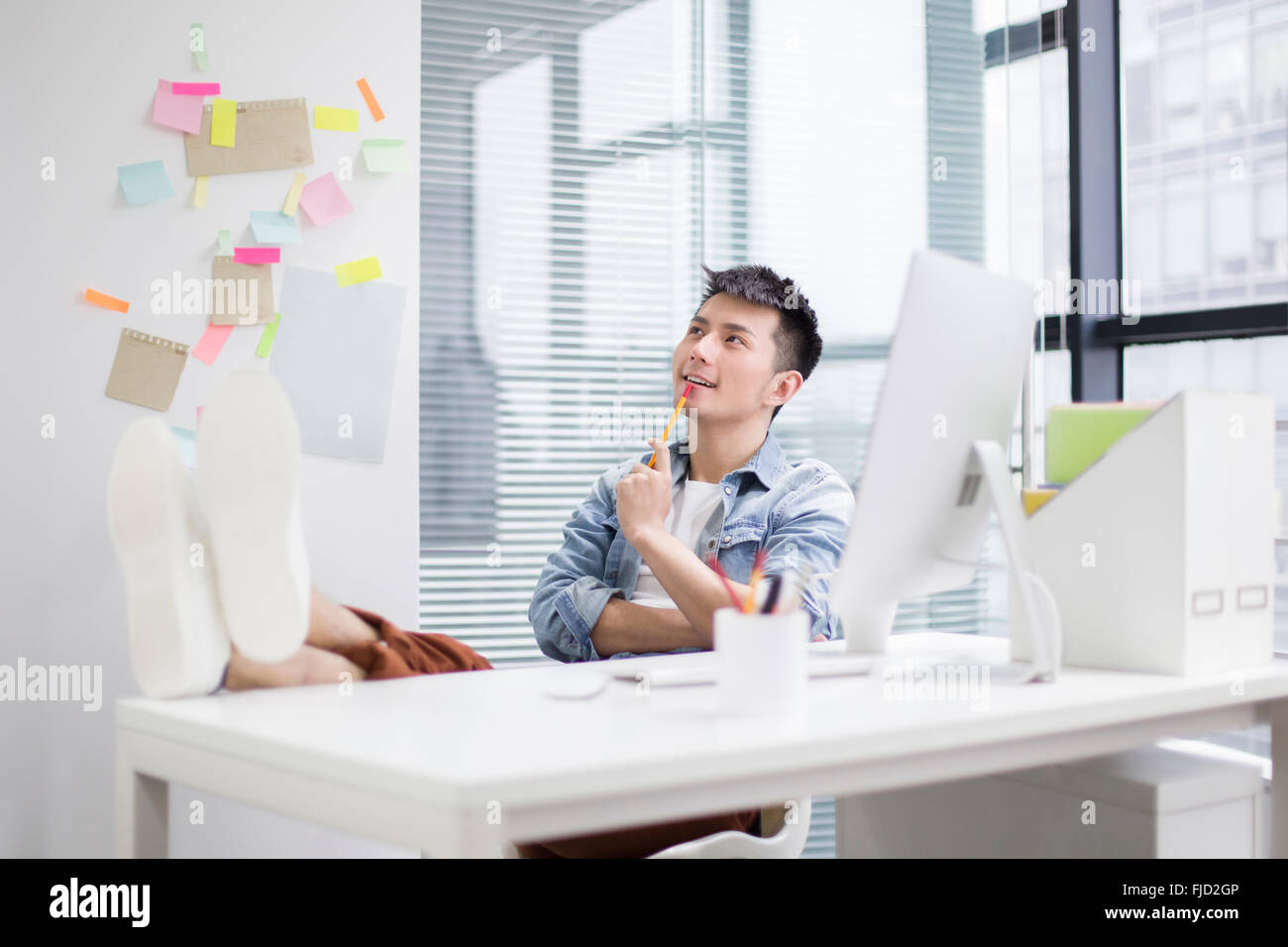 Young Chinese man thinking in office Stock Photo - Alamy