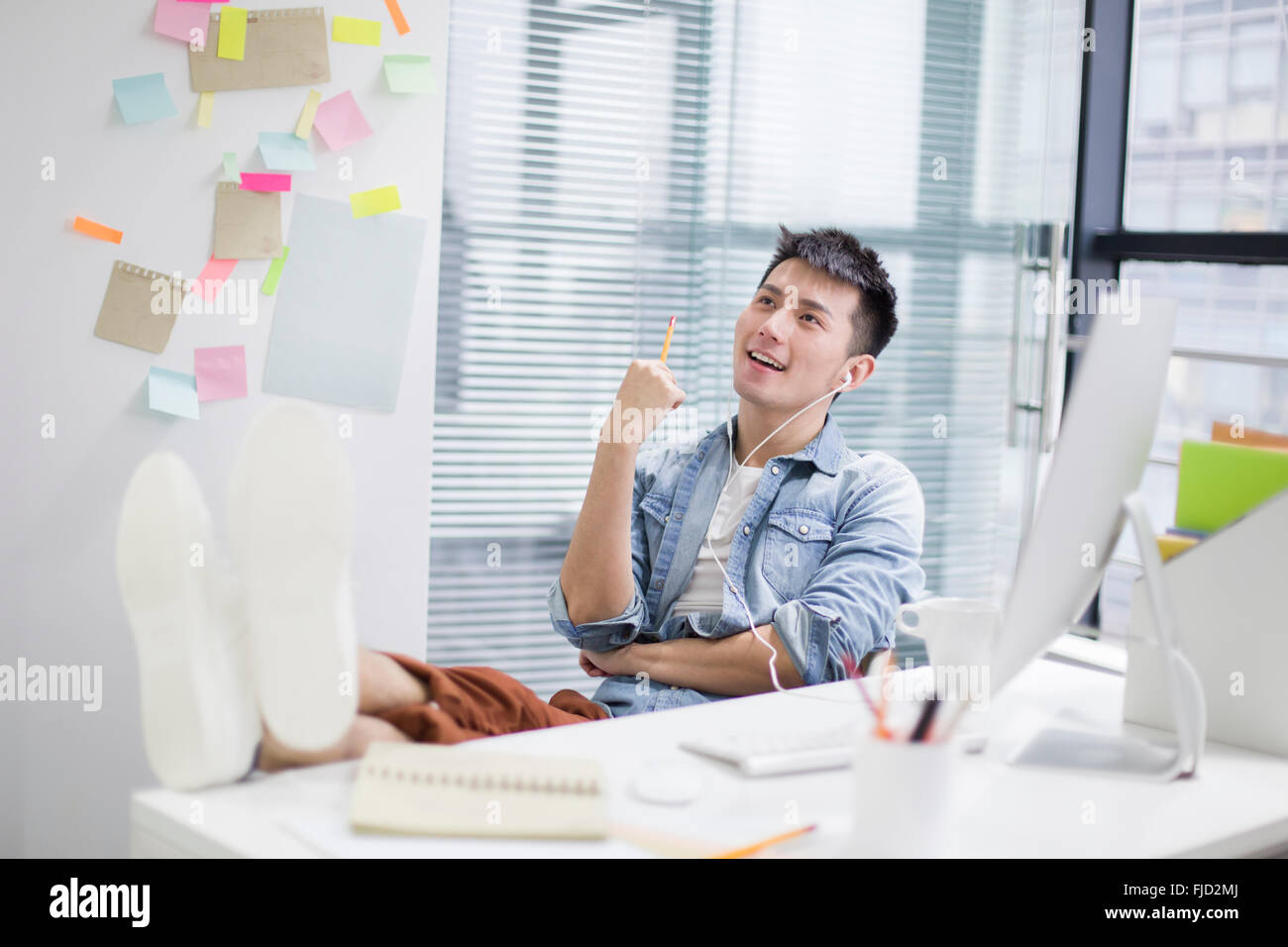 Young Chinese man thinking in office Stock Photo - Alamy