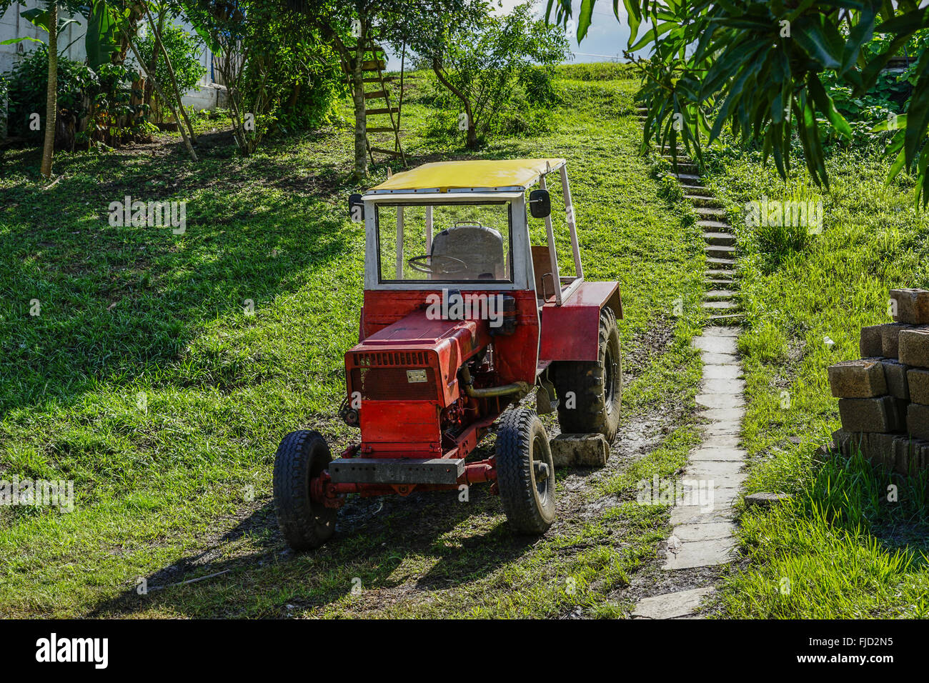 old red tractor, parked on the green grass. The brakes are uncertain ...