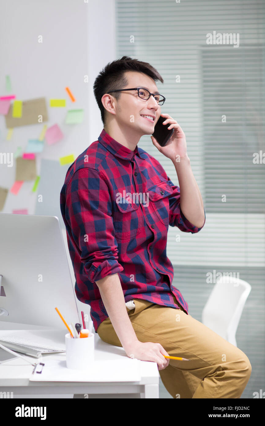 Young Chinese man talking on the phone in office Stock Photo - Alamy