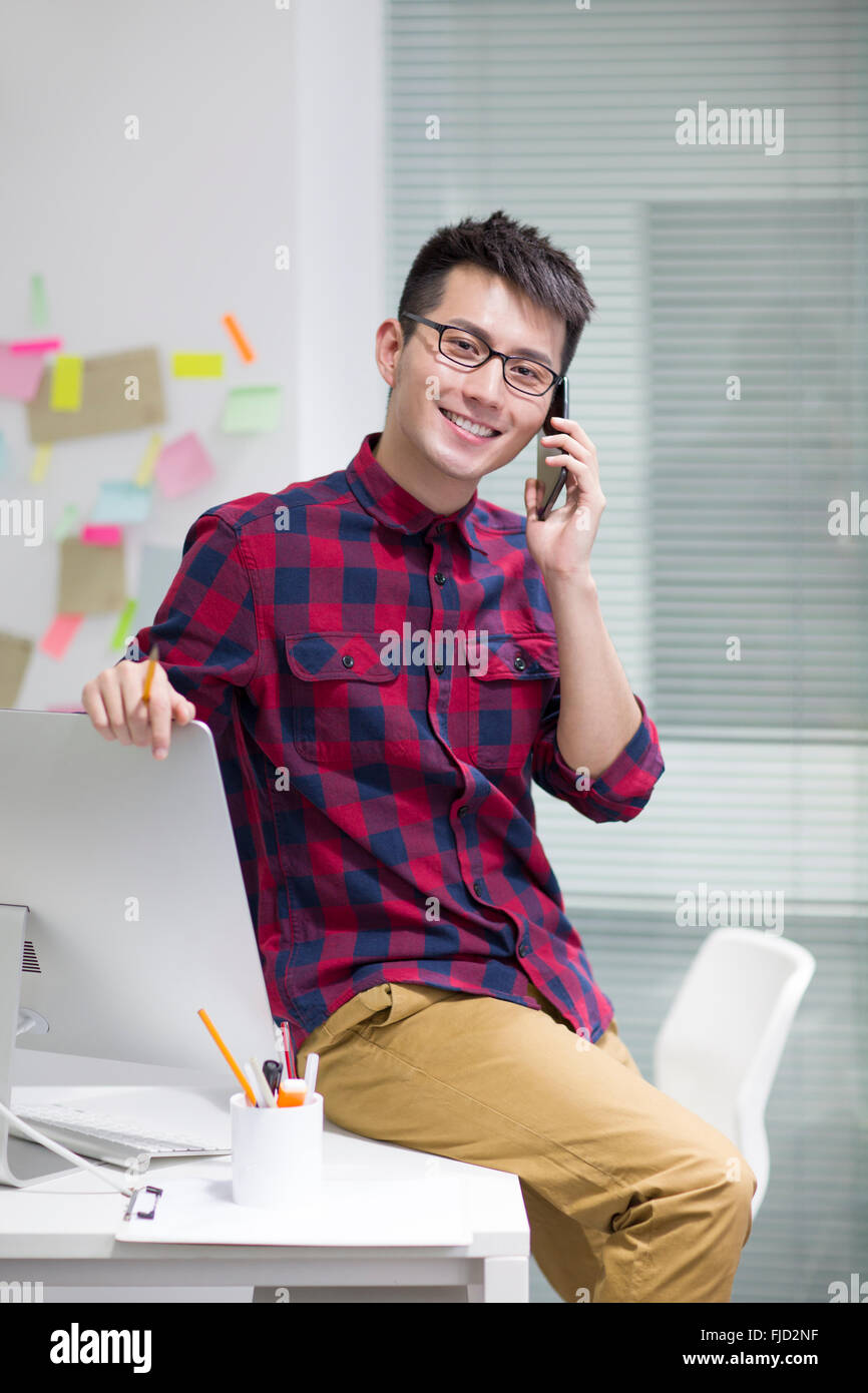 Young Chinese man talking on the phone in office Stock Photo - Alamy