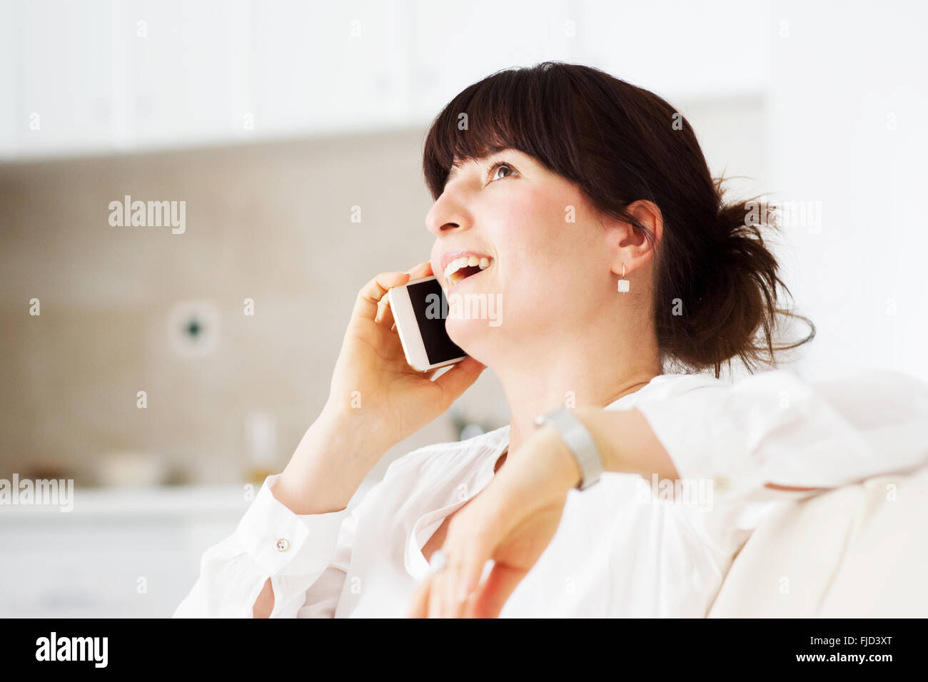 Woman in her home using mobile phone to communicate with her friends ...