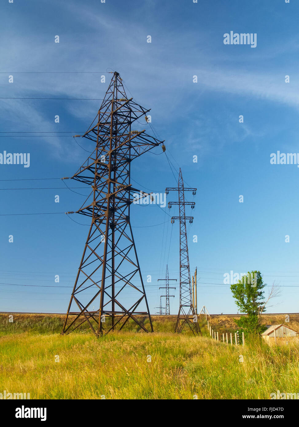 Electric power transmission lines in the field next to small house ...