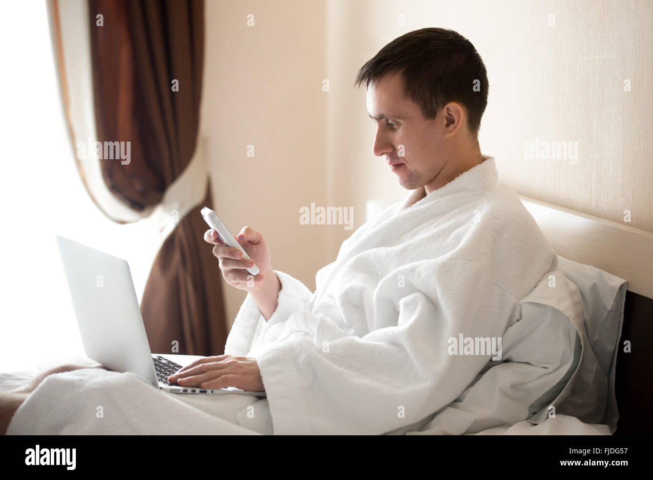 Portrait of attractive relaxed young man wearing white bath robe ...