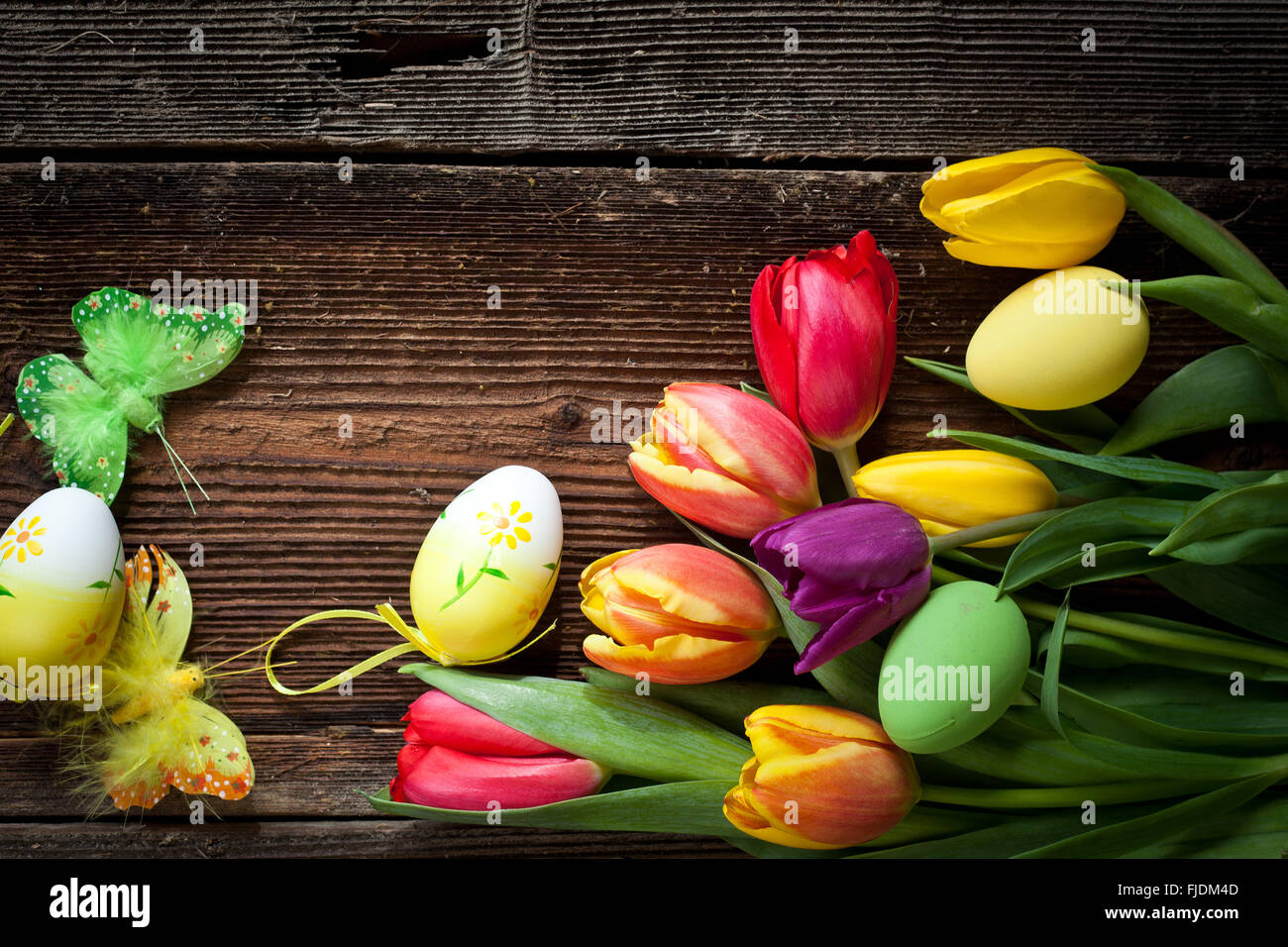 Easter eggs and fresh spring tulips on weathered wooden background ...