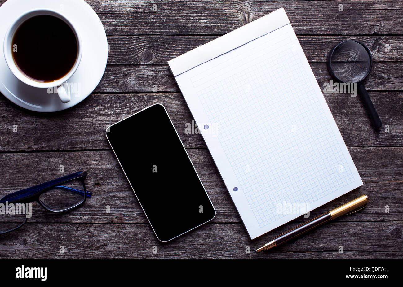 Workplace flat lay from above view. Opened notepad, phone, glasses, a ...