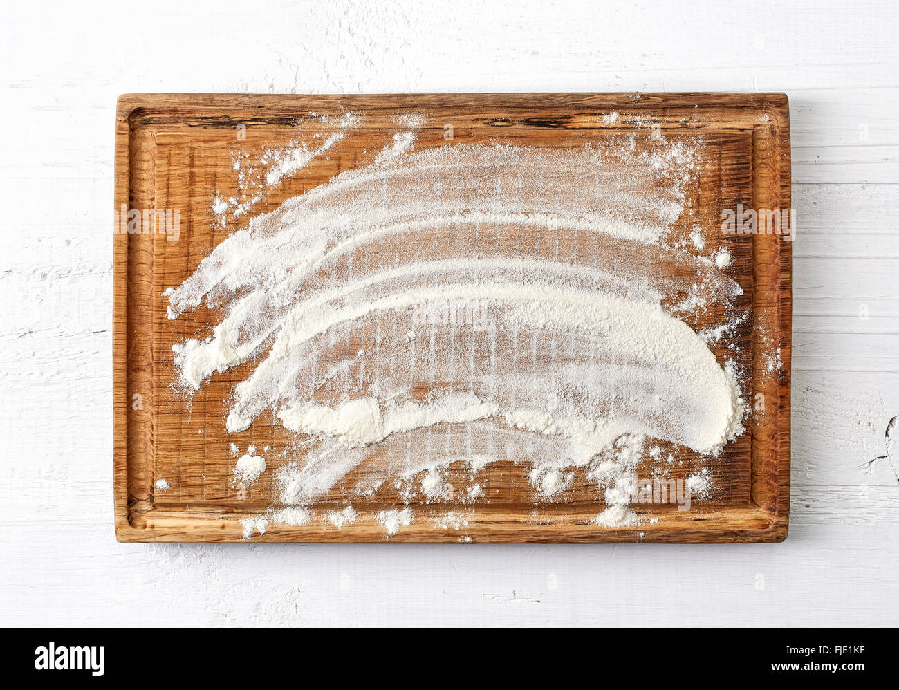 White flour on wooden cutting board on white wooden table, top view ...