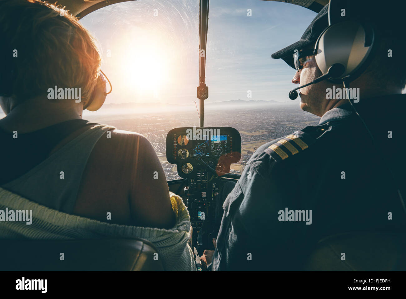 Rear view of male and female pilots flying a helicopter on sunny day ...
