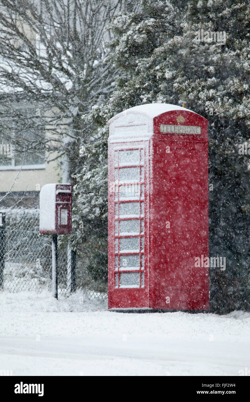Snow covered red BT telephone box and red Royal Mail letter box on a ...
