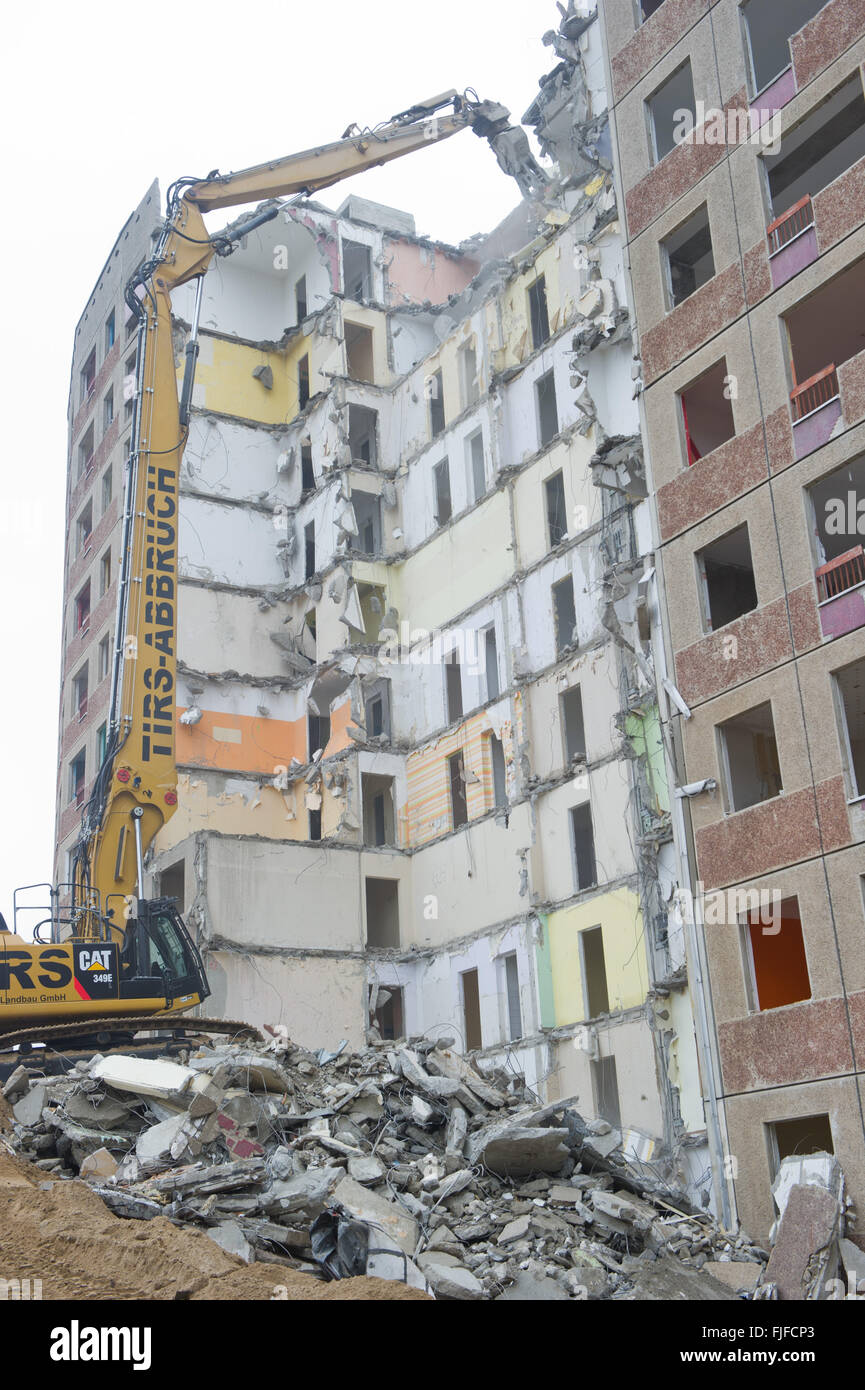 An excavator from a demolition company razes a Plattenbau building from ...