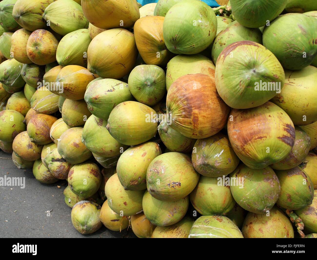 Large clusters of coconuts are stored on the sidewalk by a coconut ...