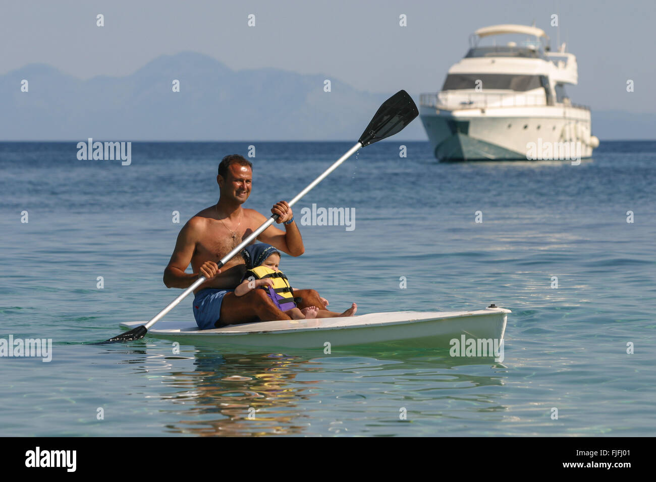 father and daughter paddling a canoe at Koukounaries beach, Skiathos ...