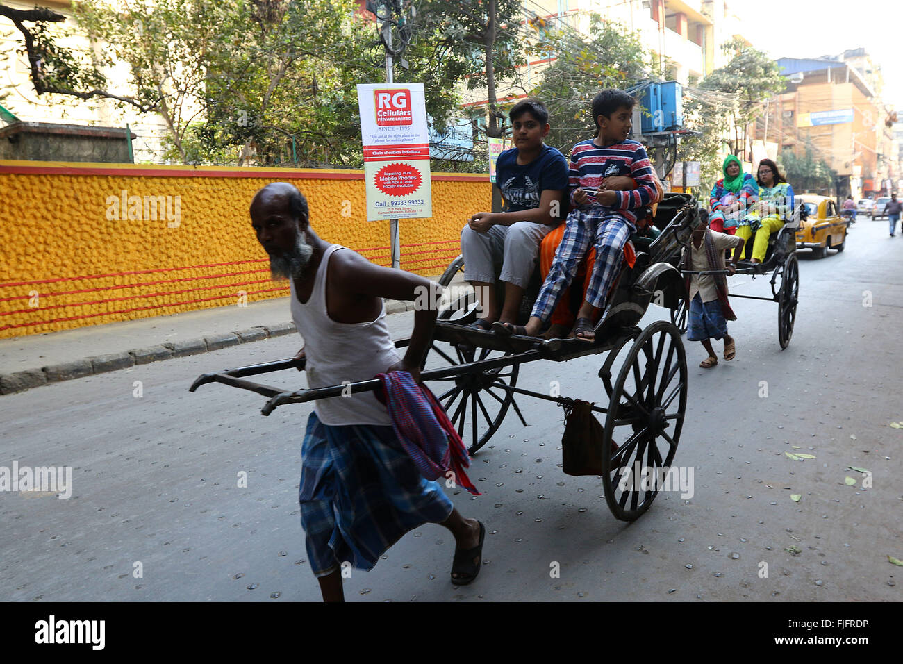 Hand pulling rickshaw puller pulling with passenger walks past a ...