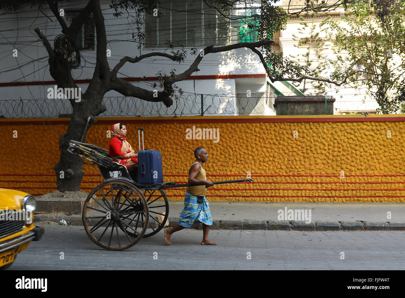Hand pulling rickshaw puller pulling with passenger walks past a ...