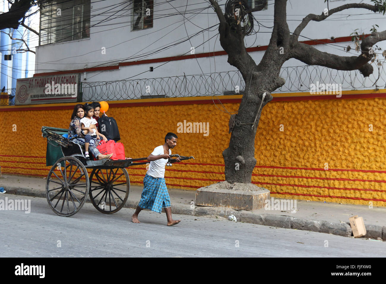 Hand pulling rickshaw puller pulling with passenger walks past a ...