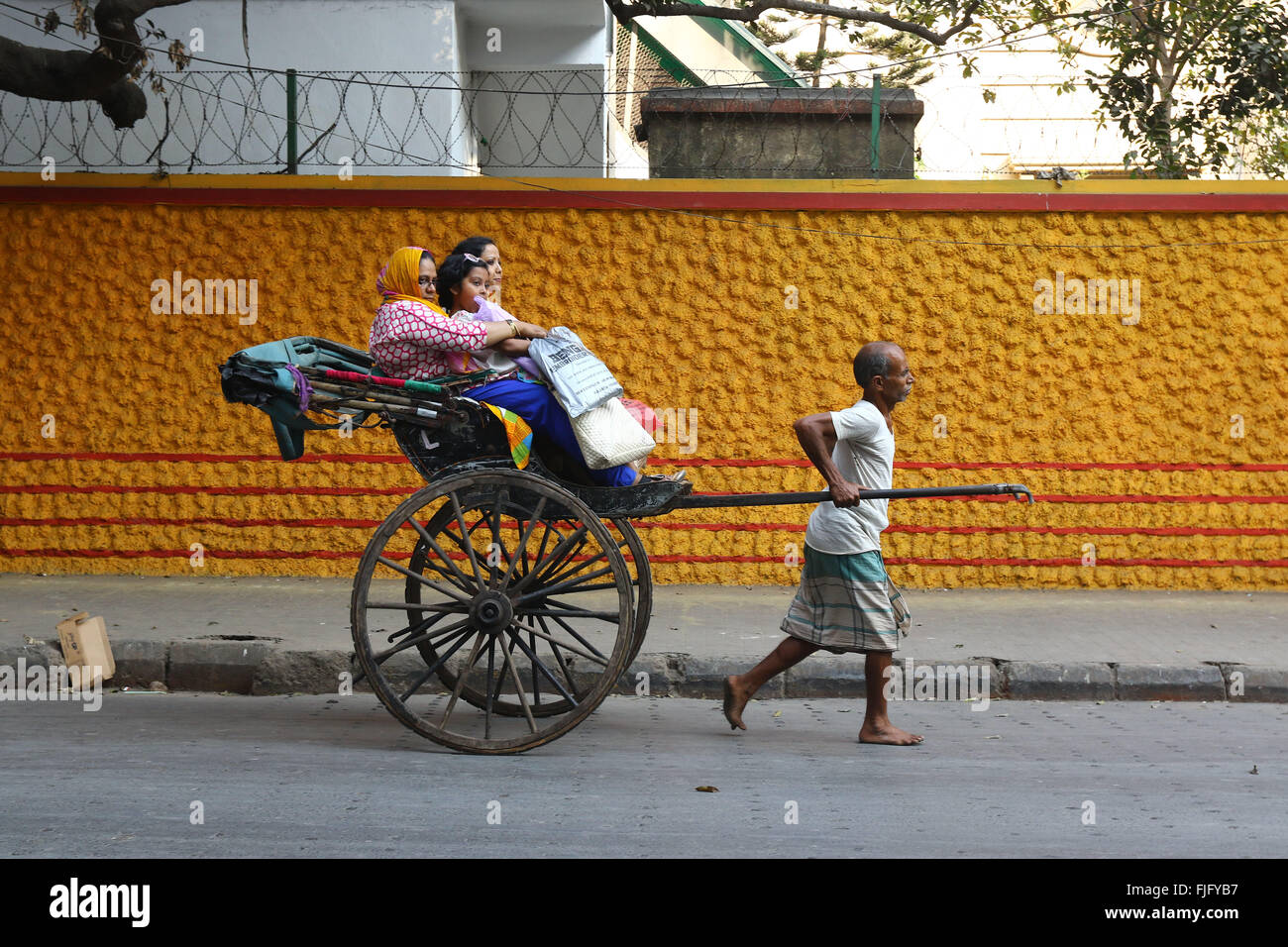 Hand pulling rickshaw puller pulling with passenger walks past a ...