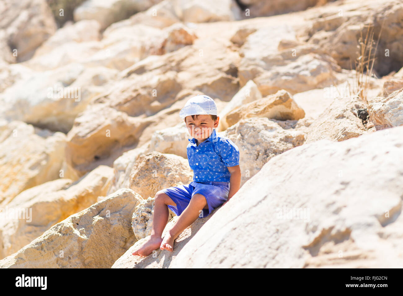 Little boy sitting on rock on a sunny day Stock Photo - Alamy