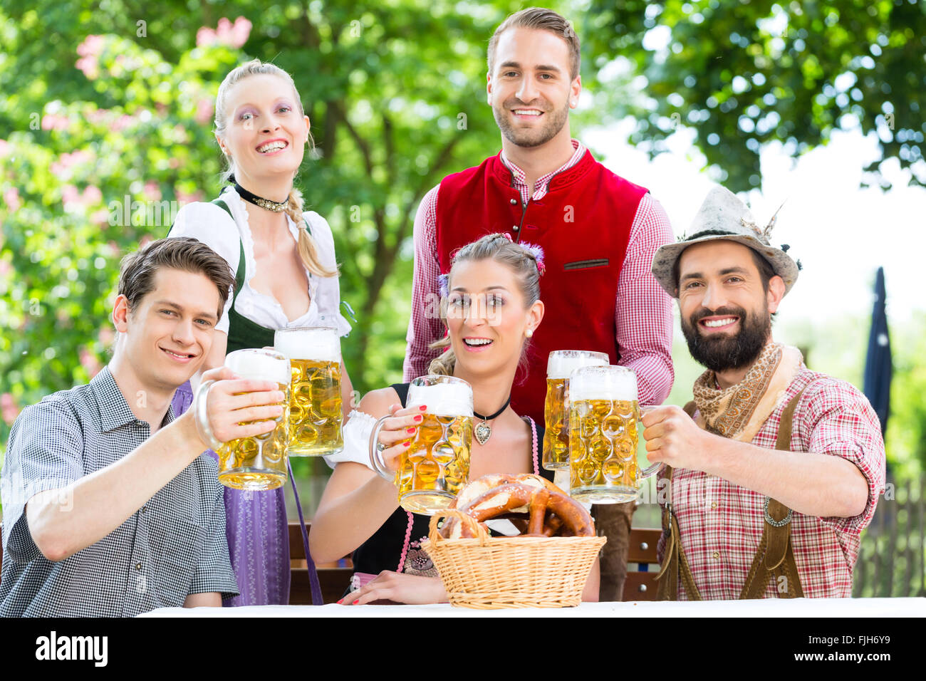 In Beer garden - friends in Tracht, Dirndl and Lederhosen drinking a ...