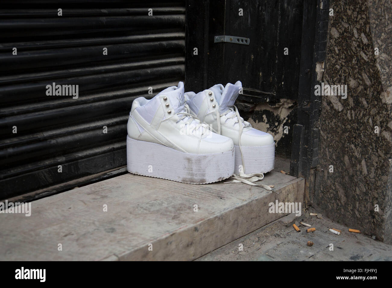 Pair of abandoned platform style trainers, discarded in a doorway ...