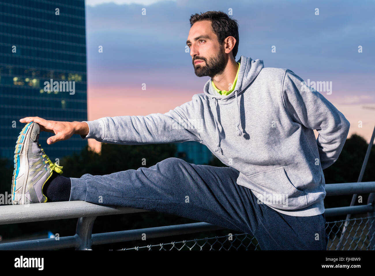 Runner stretching in front of office building at sunset Stock Photo - Alamy