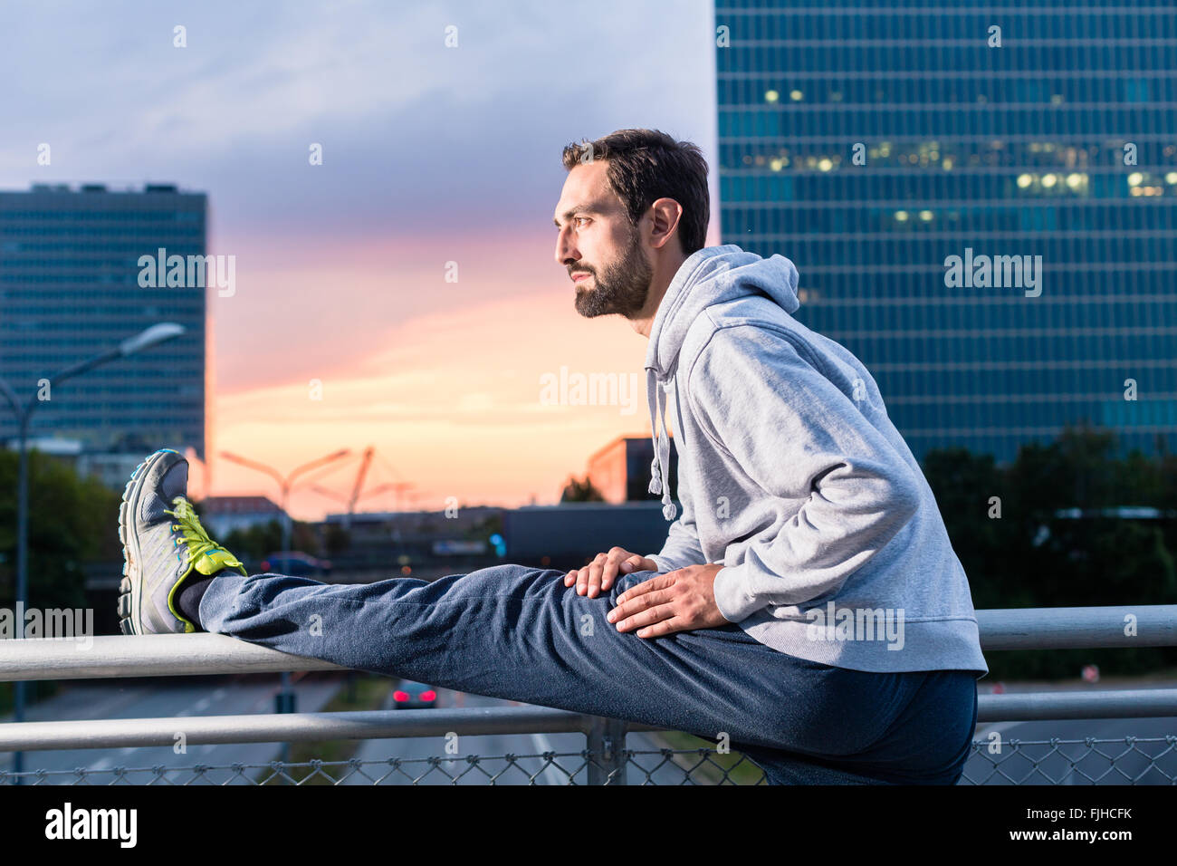 Runner stretching in front of office building at sunset Stock Photo - Alamy