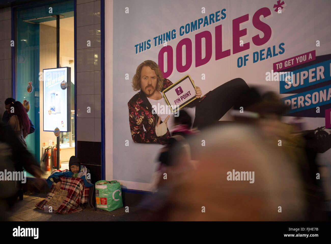 Homeless man begging next to financial advertising poster in the busy ...