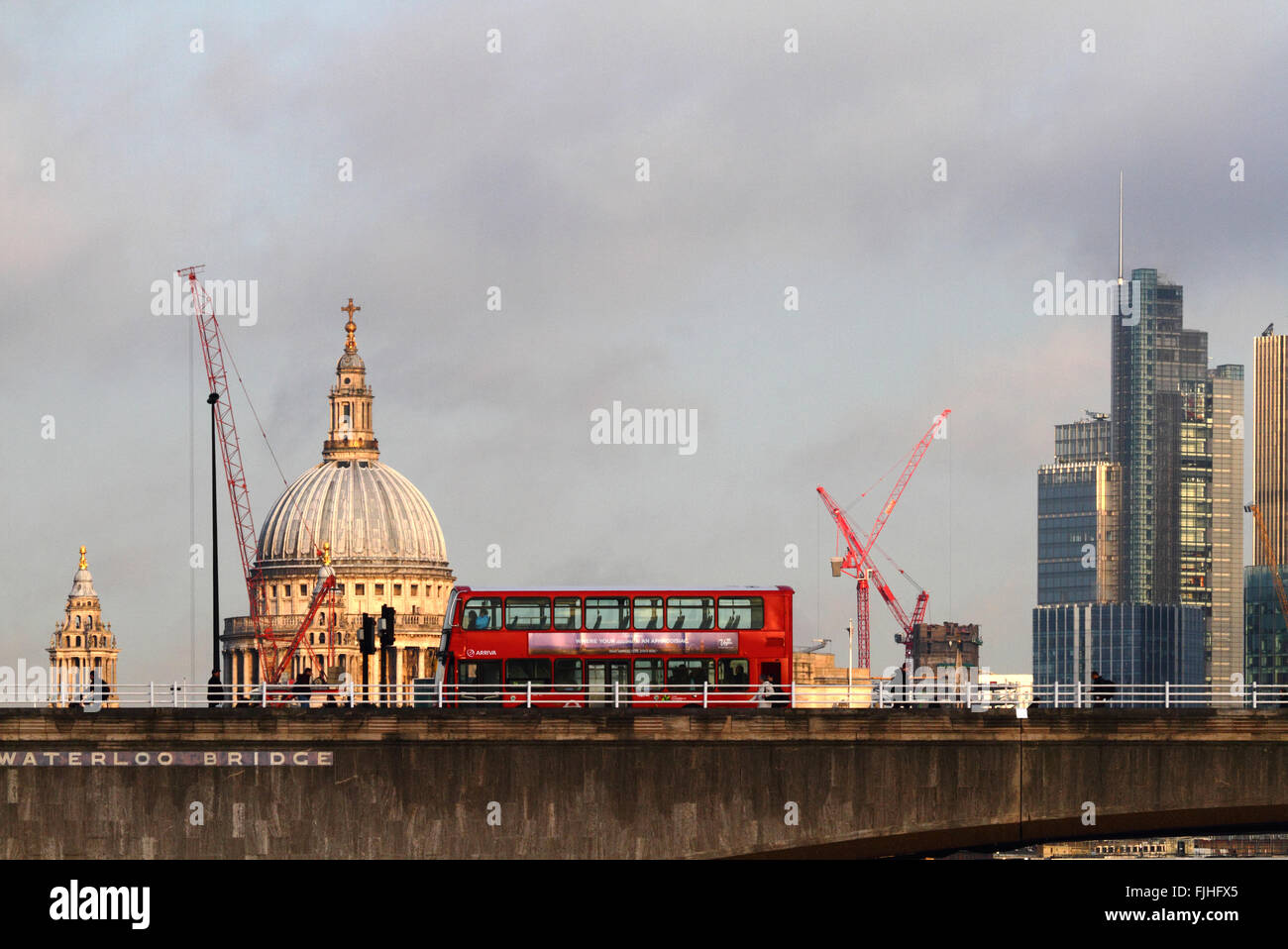 Red double deck bus crossing Waterloo Bridge, St Paul's Cathedral dome ...