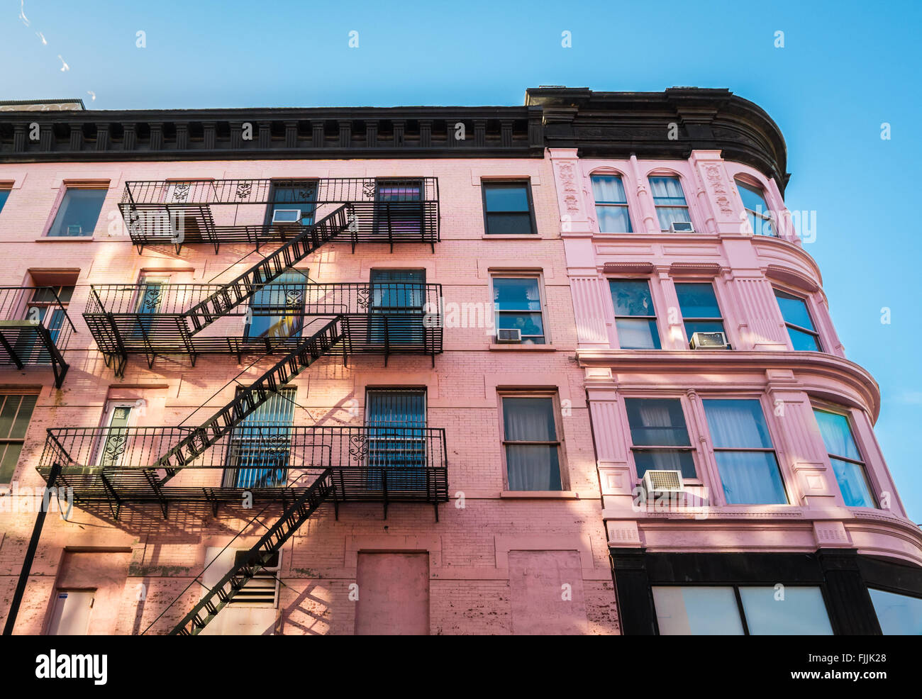 Pink old traditional building in New York City with metal fire escapes ...