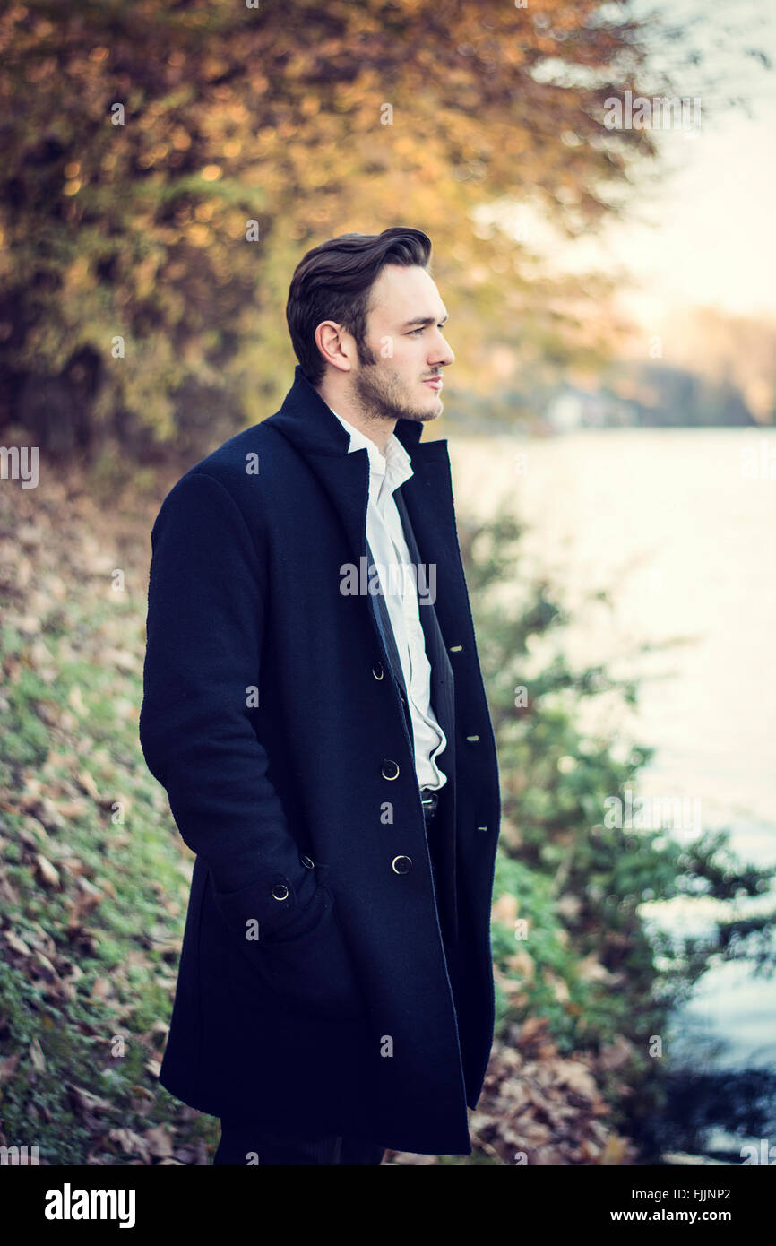 Handsome young man outdoor in winter fashion, wearing black coat and ...