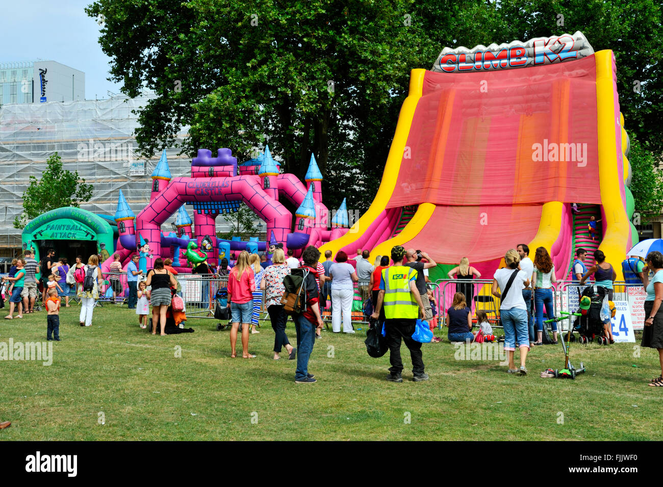 Children playing on giant inflatable activities at festival with screen ...