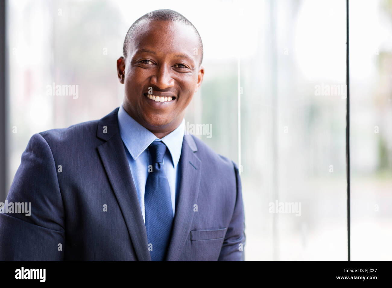cheerful African business man standing by office window Stock Photo - Alamy