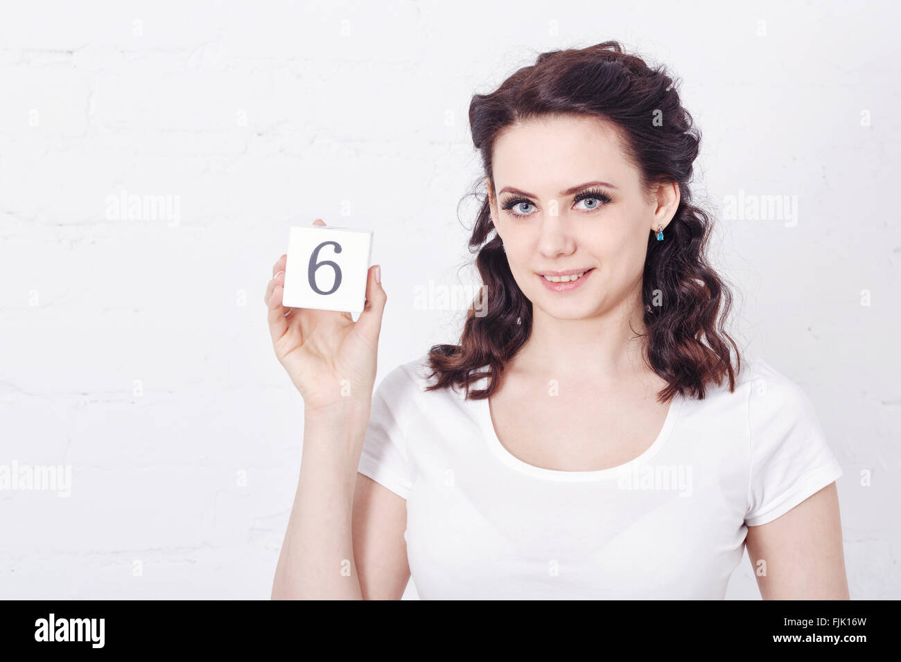 Young cute girl smiling and holding a number six. Girl dressed in a ...