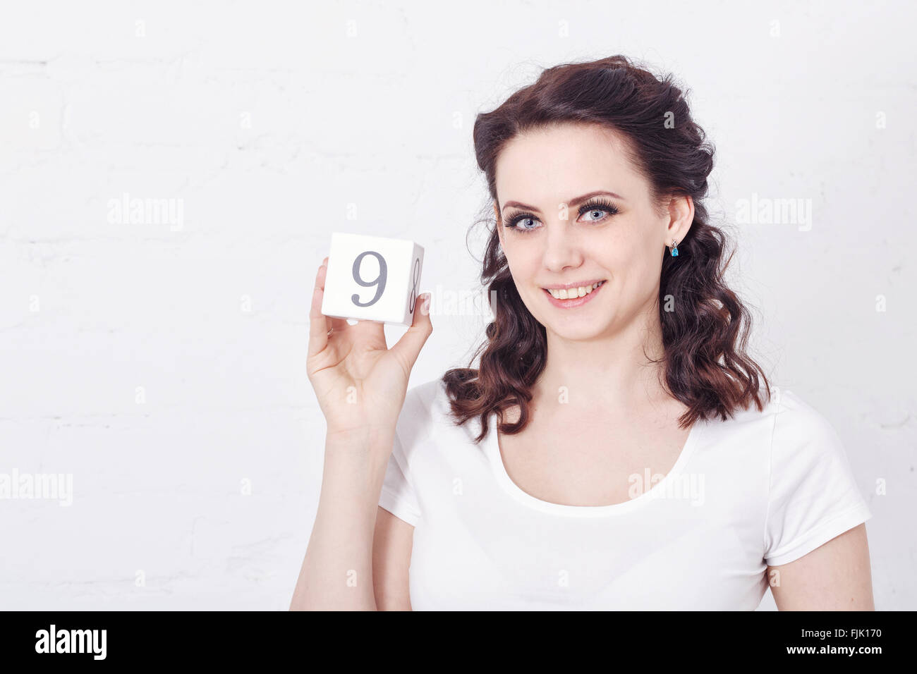 Young cute girl smiling and holding a number nine. Girl dressed in a ...