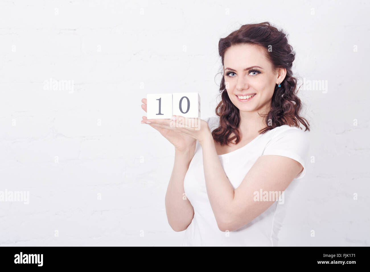 Young cute girl smiling and holding a number ten. Girl dressed in a ...